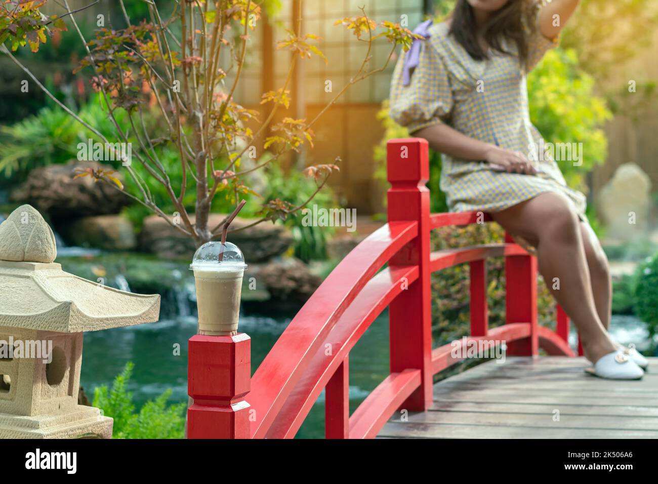 Iced cappuccino with straws placed on head of red wooden bridge with ...