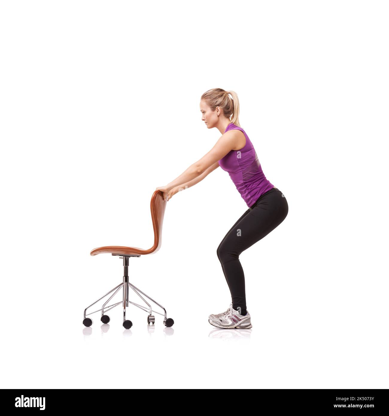 Crouching to strengthen her core. A beautiful young woman wearing gym ...