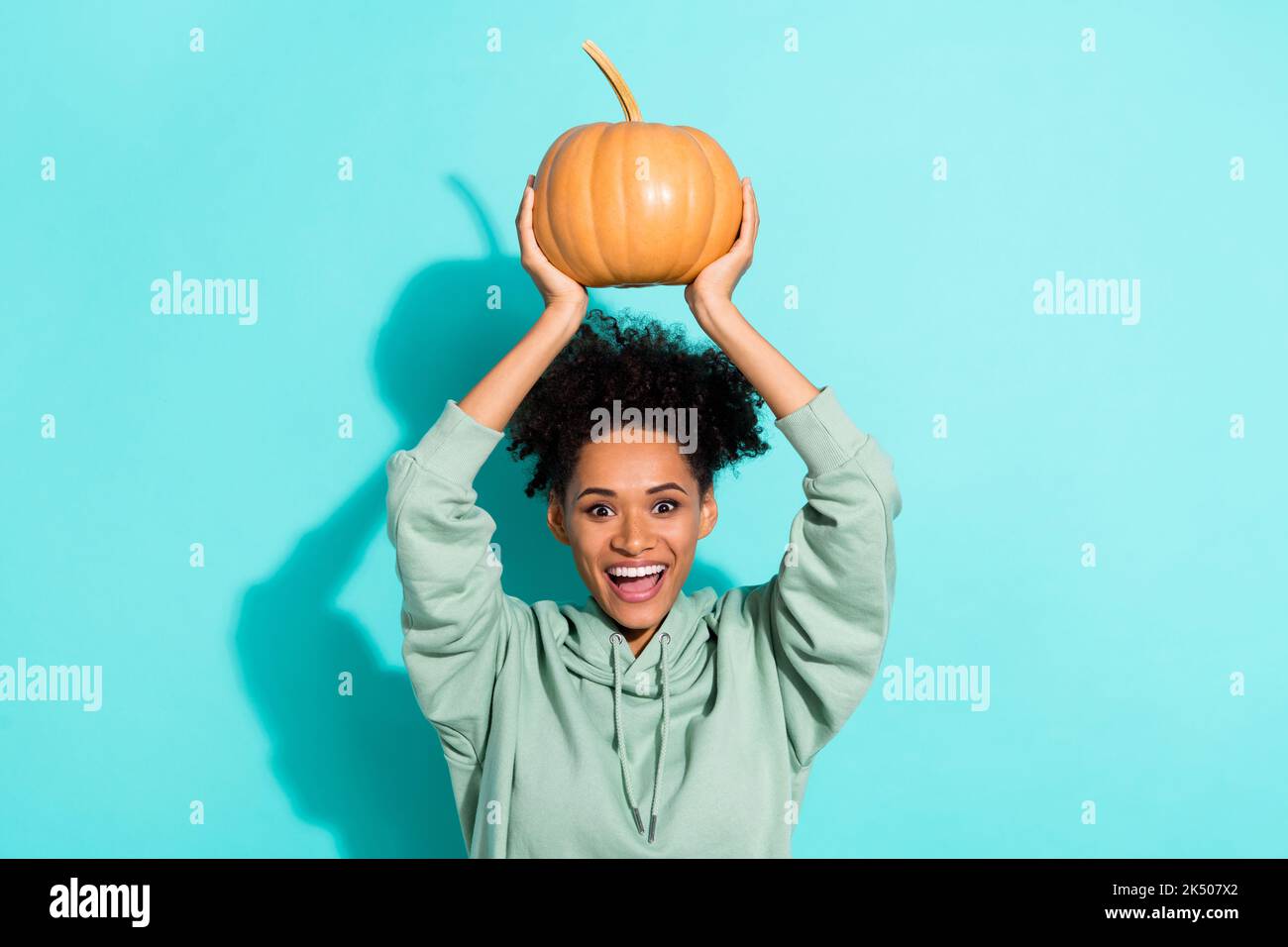 Portrait of positive overjoyed girl arms hold pumpkin above head good ...