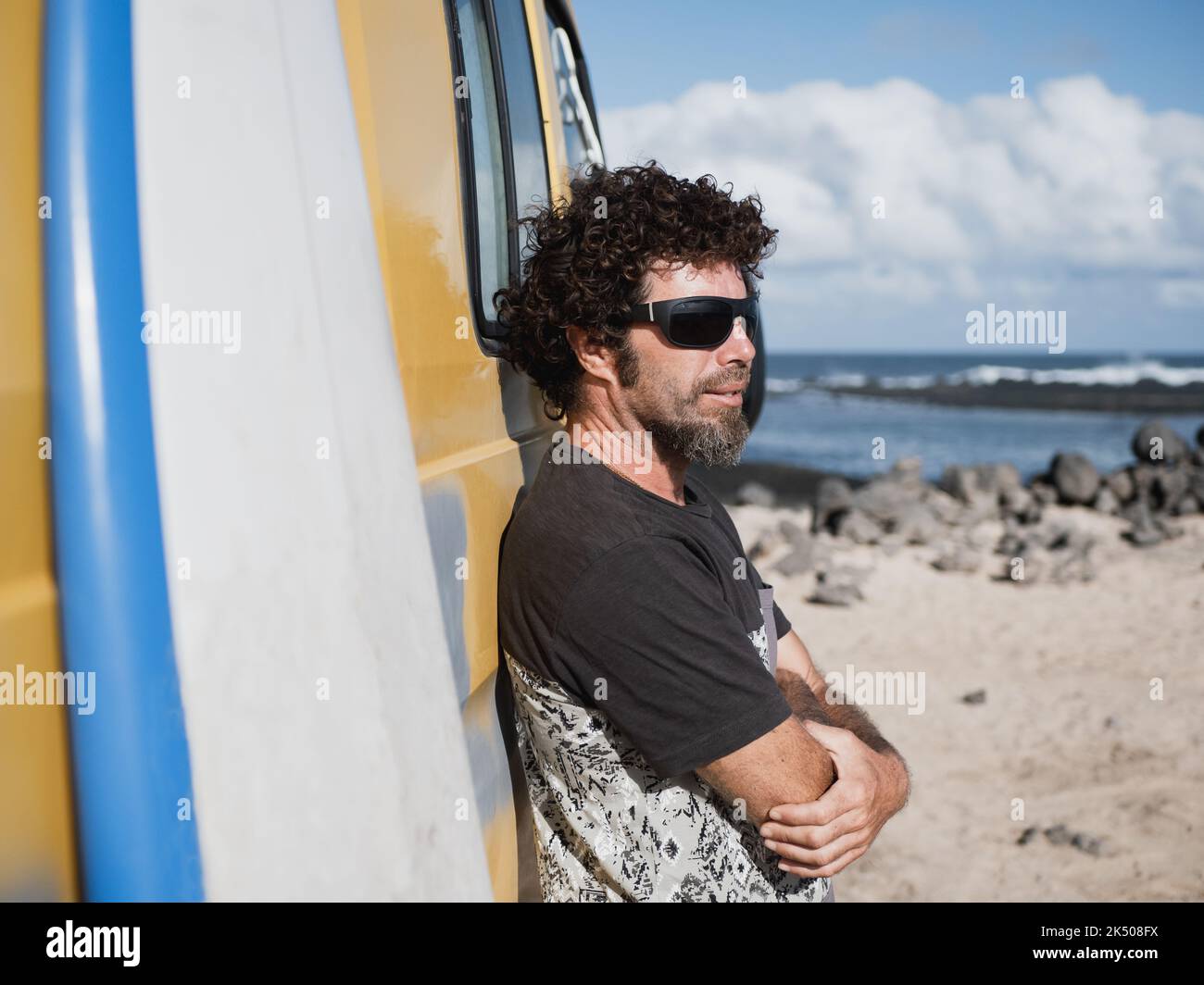 Caucasian nomad man portrait by the sea leaning on his camper van. His ...