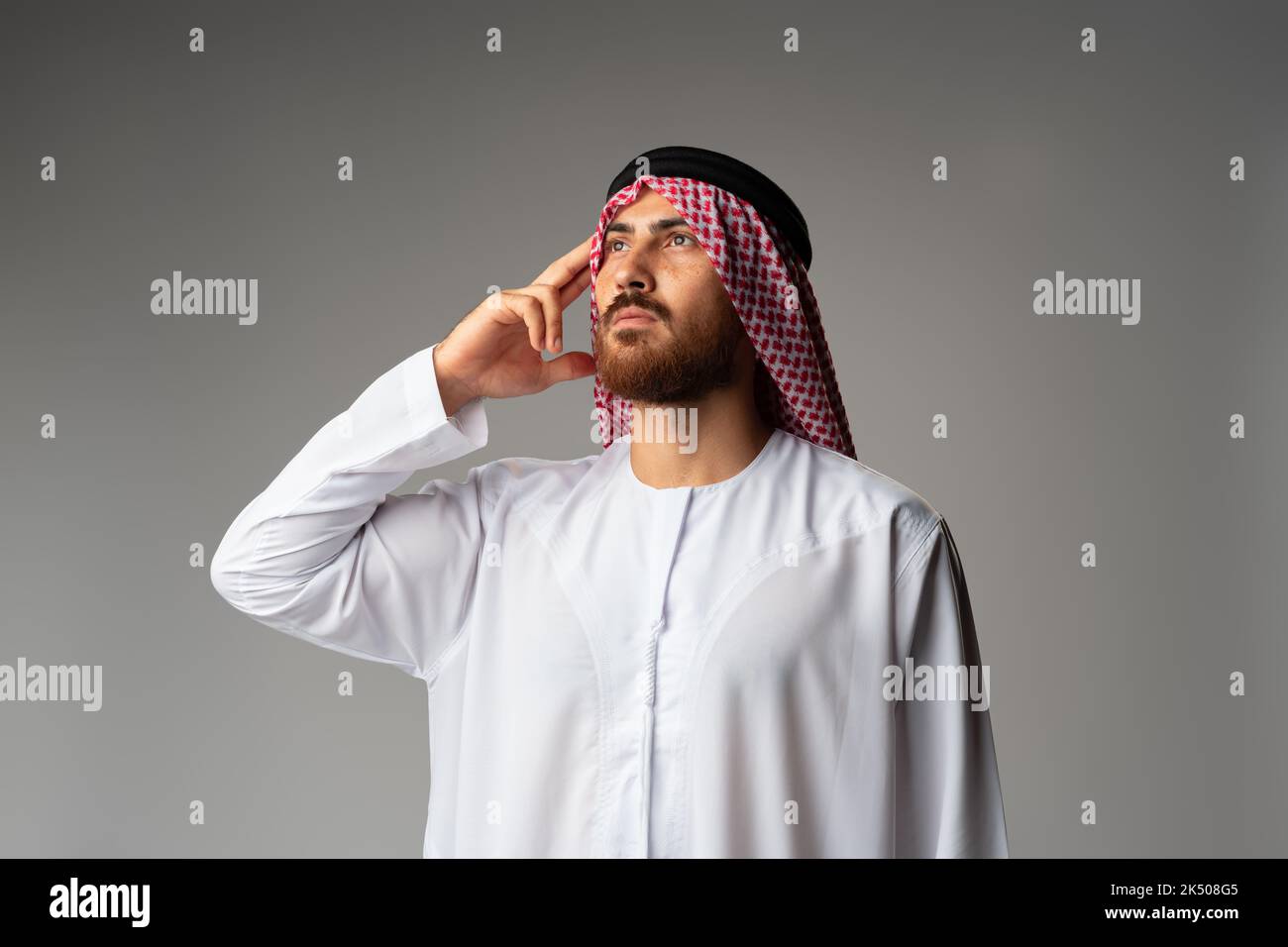 Young arab man wearing traditional clothes thinking about something ...