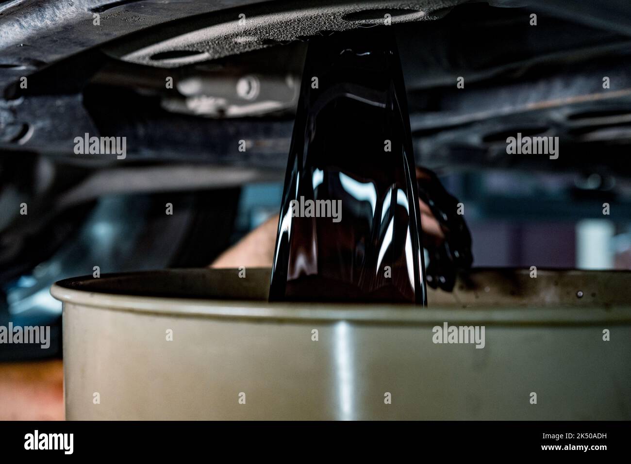 Old dirty oil pouring from the car engine in car service station close ...
