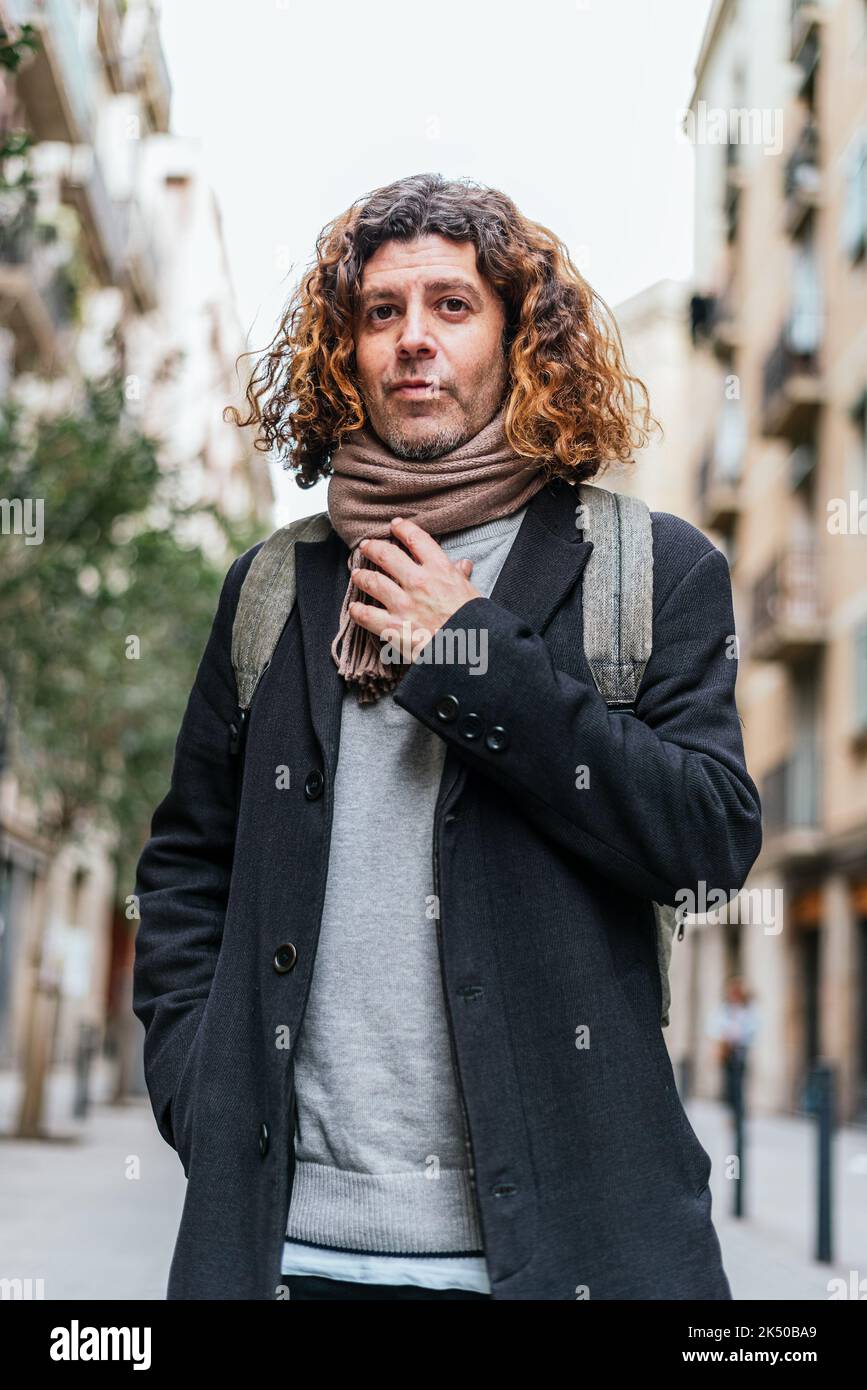 Low angle of self assured male in smart casual clothes with backpack ...