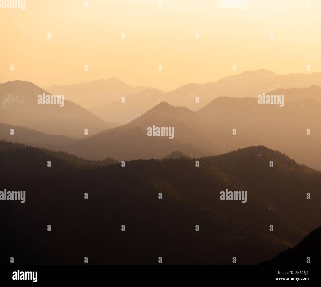 An aerial view of layered mountains covered with green forests at ...
