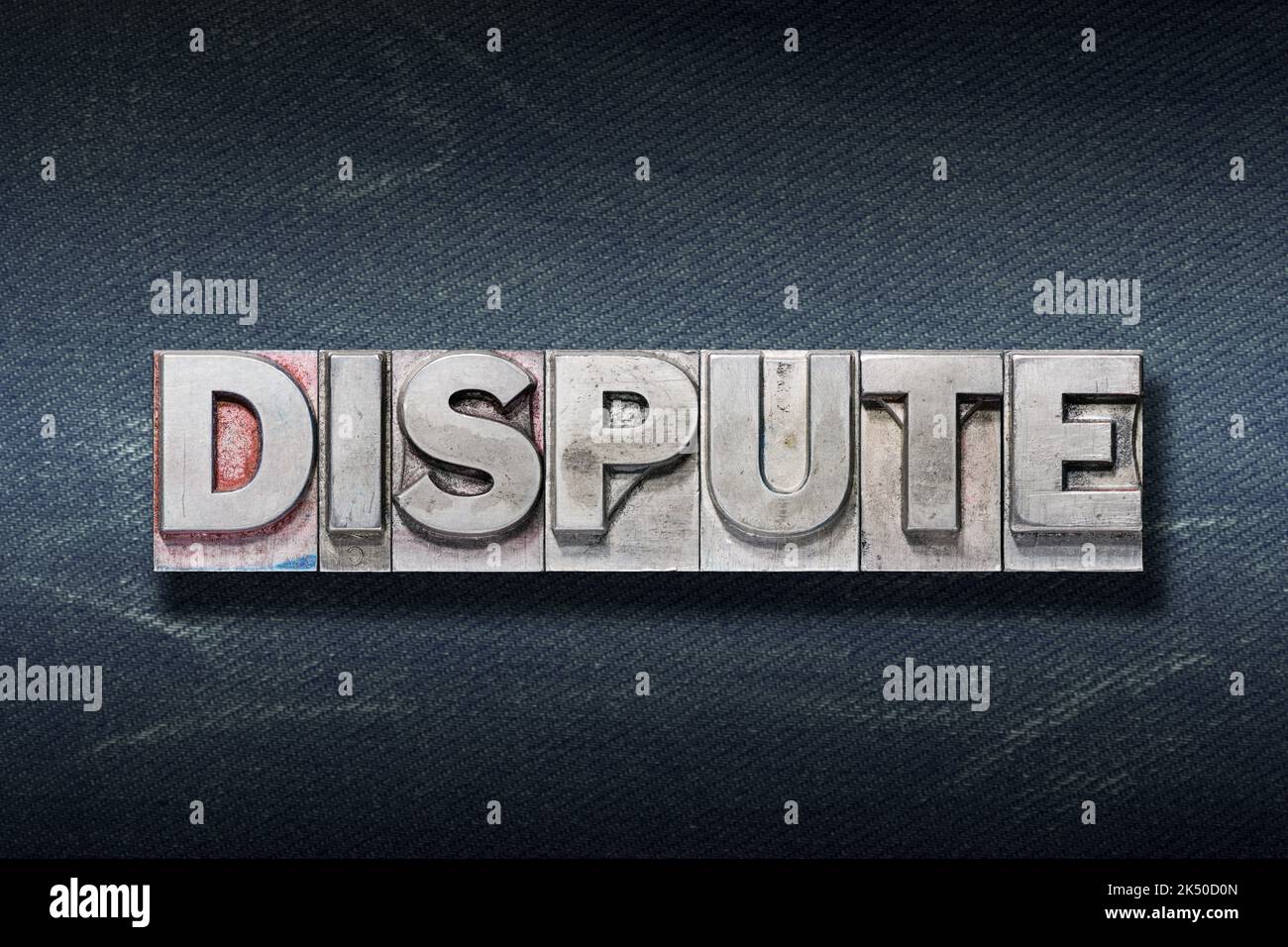 dispute word made from metallic letterpress on dark jeans background ...