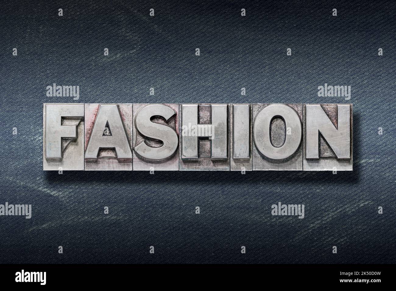 fashion word made from metallic letterpress on dark jeans background ...