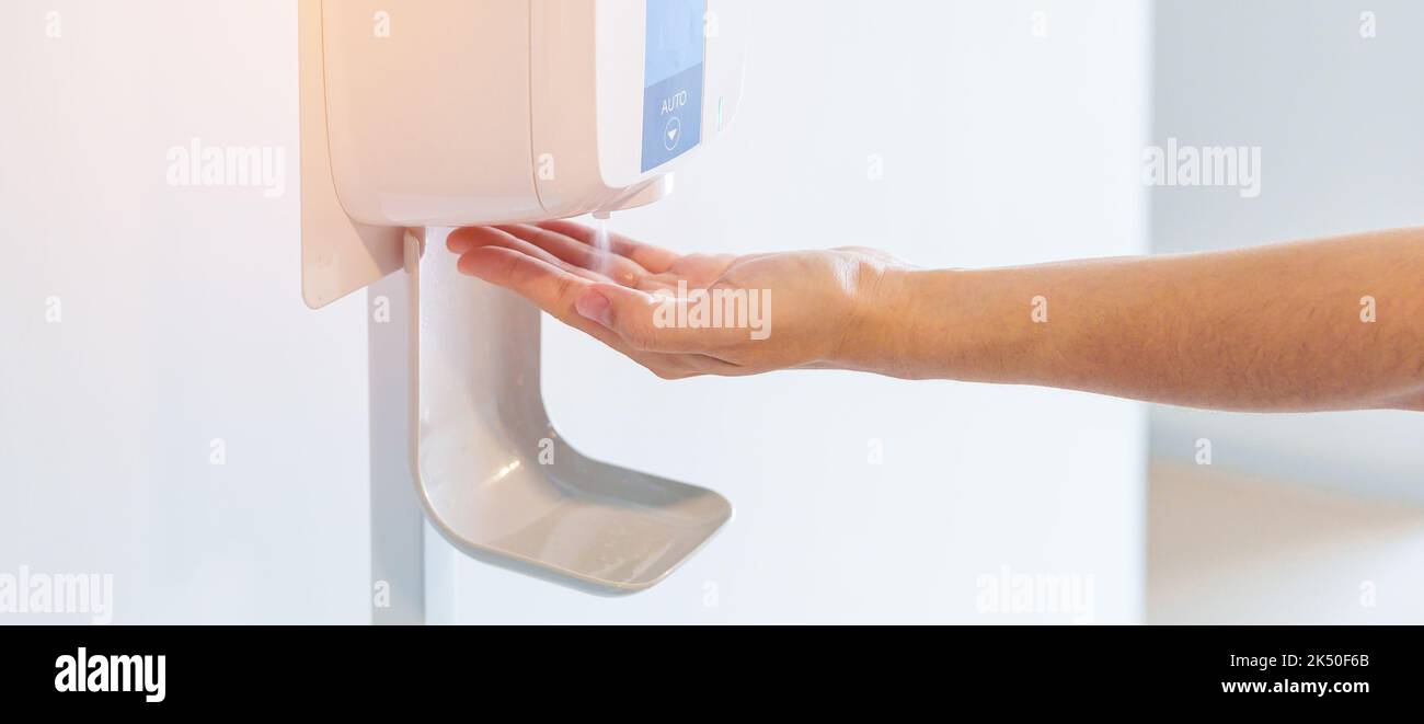 hand spray by automatic sanitizer dispenser in office or apartment ...