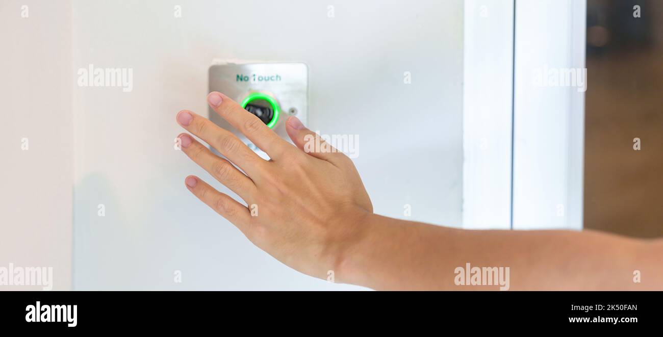 Hand open the door by No touch sensor switch on the wall at office or ...