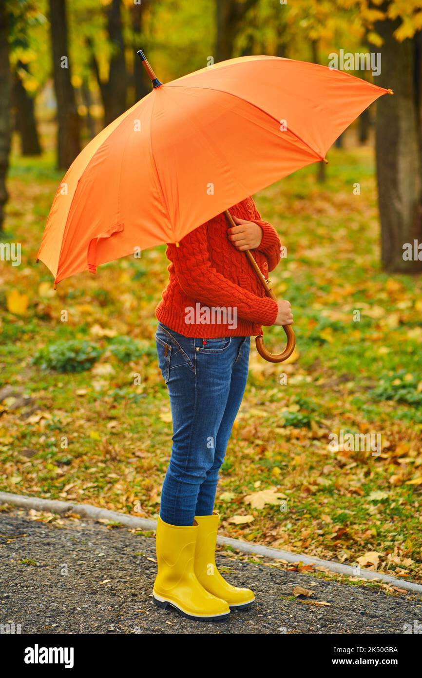 Funny unrecognizable kid under an orange umbrella Stock Photo - Alamy