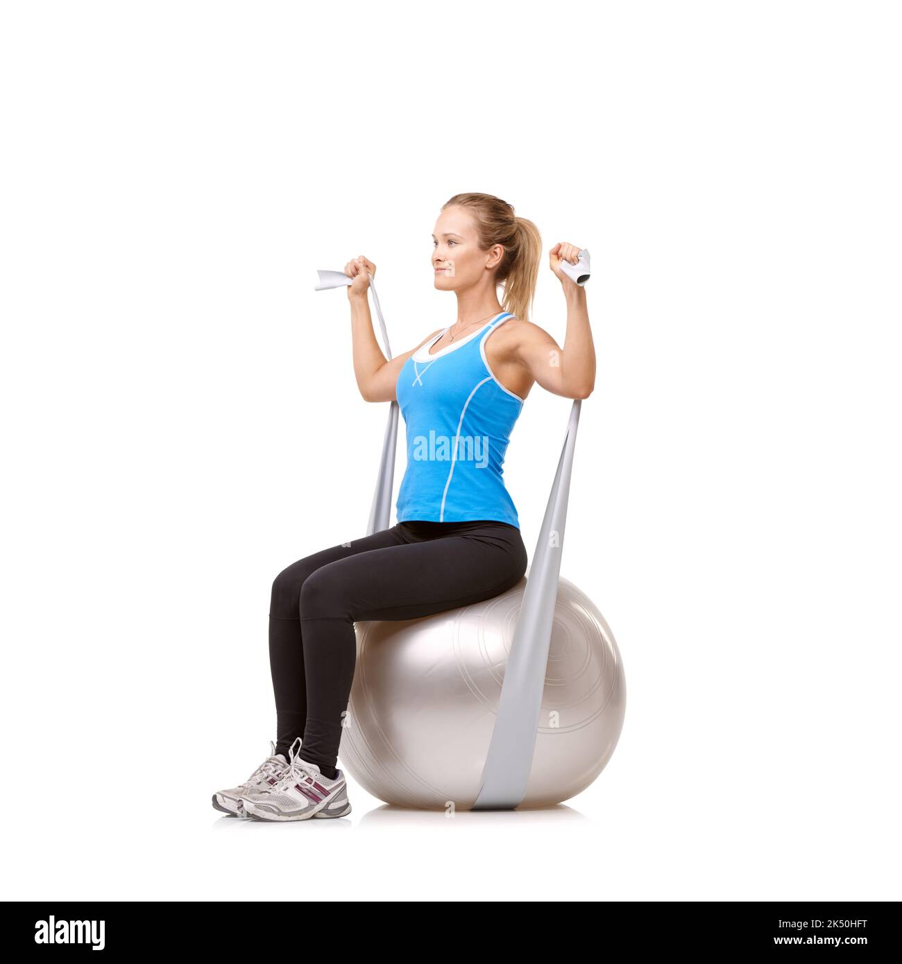 Total-body toning. A young woman sitting on an exercise ball while ...