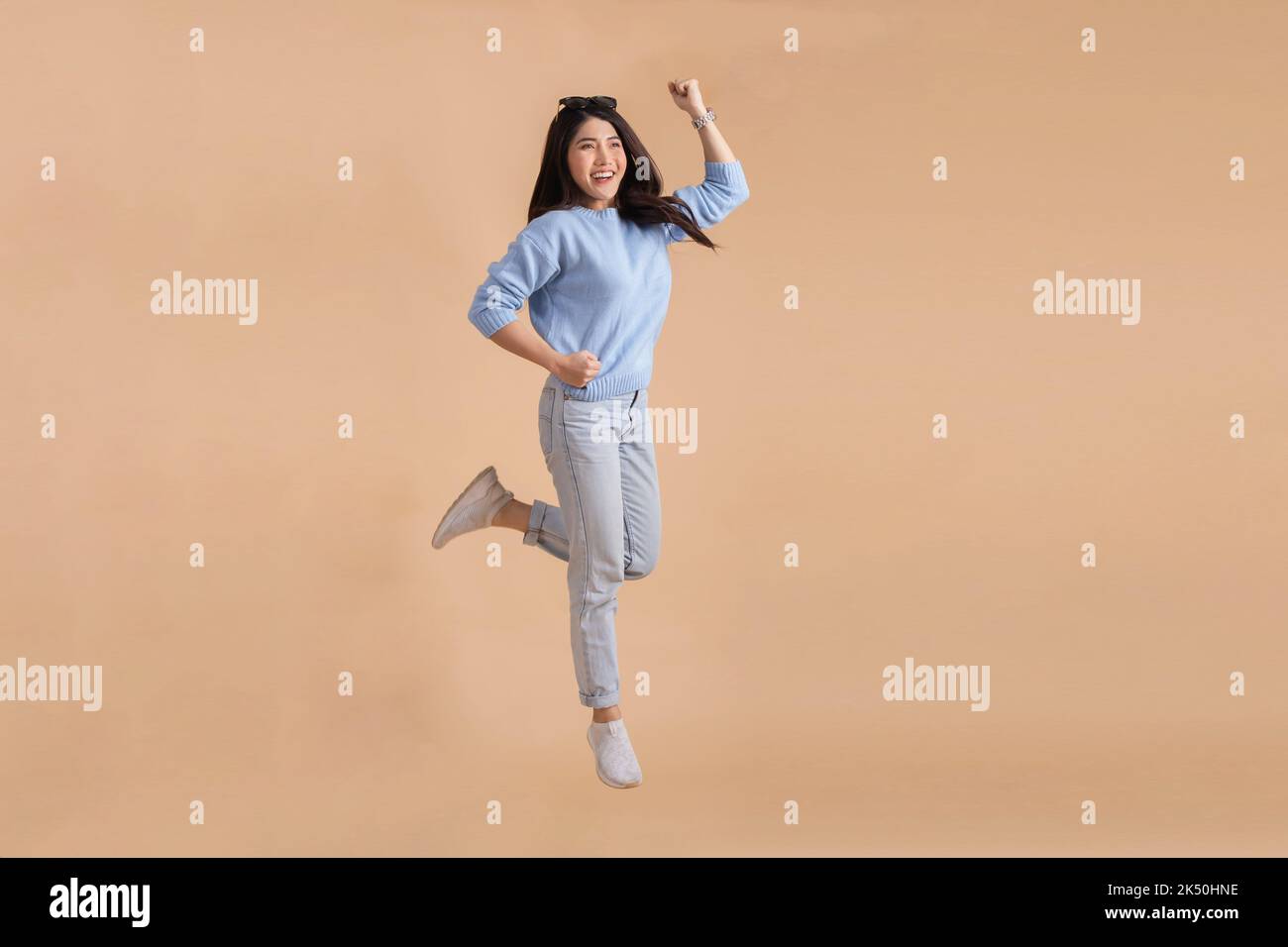 Happy smiling Asian woman with jumping in the air lifting her hands up ...