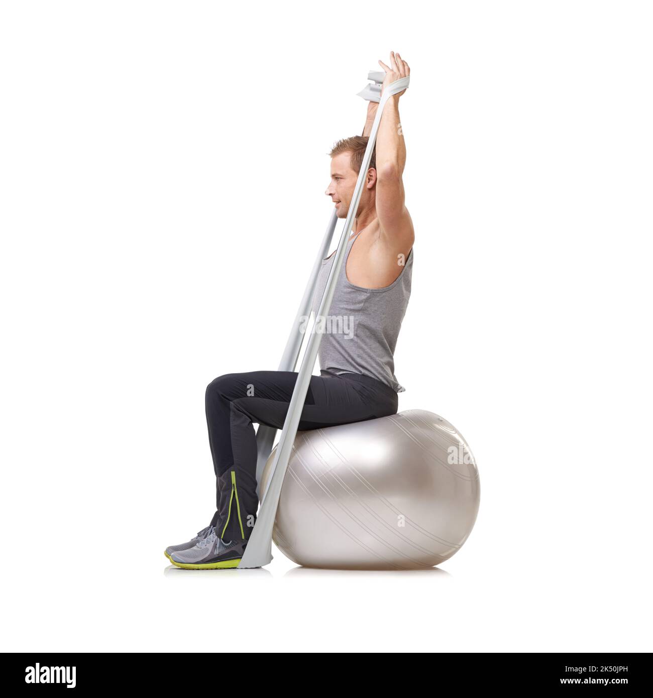 Using the tools of the toning trade. Young man sitting on a Swiss ball ...