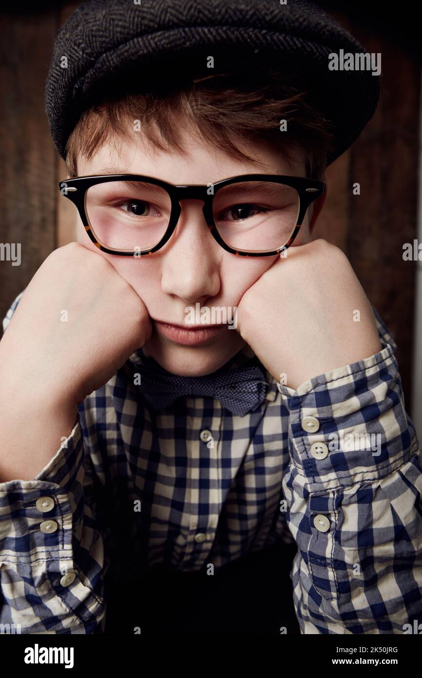 Im so bored. Young boy in retro clothing wearing spectacles with a ...