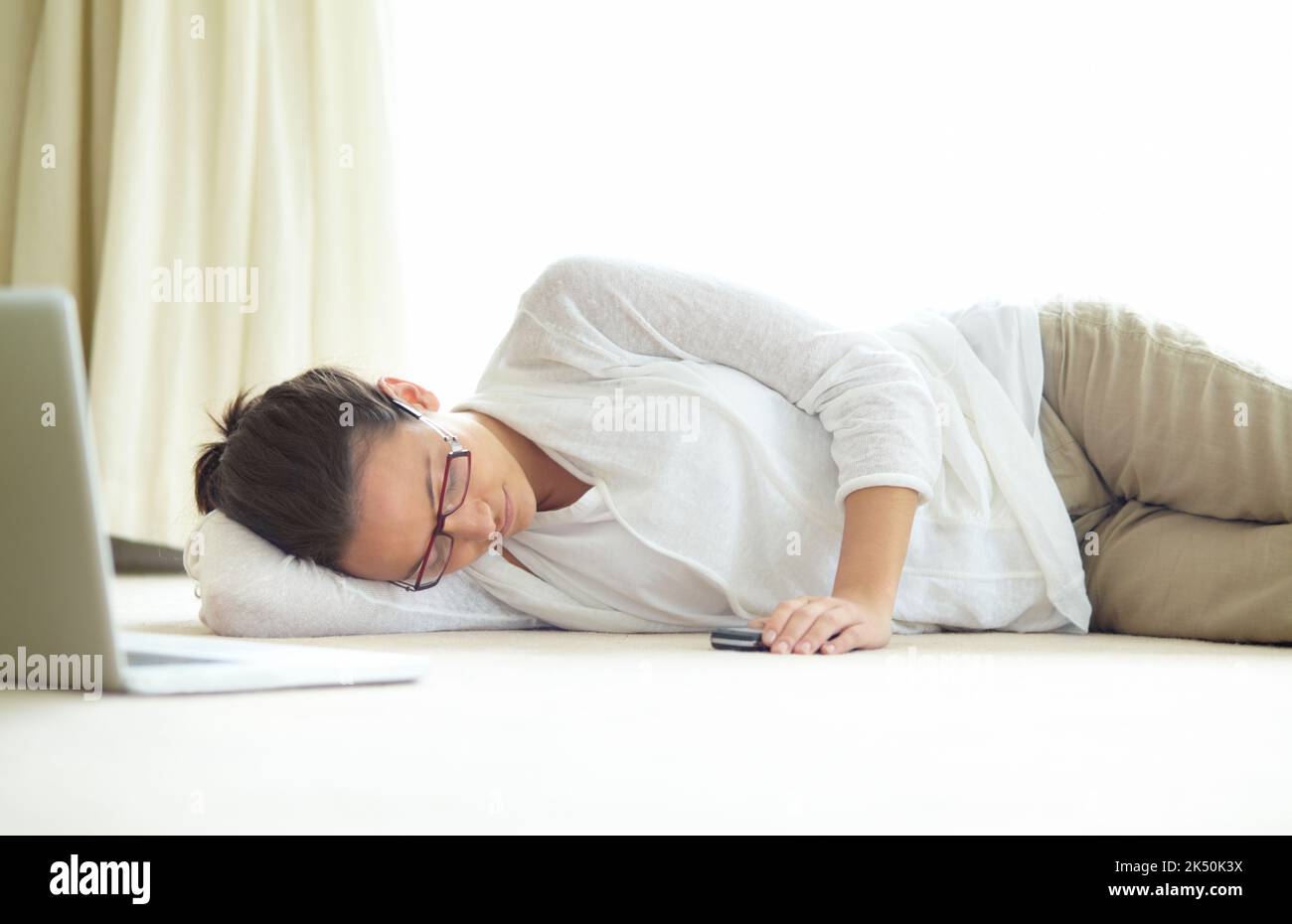 Catching a cat-nap. A tired young woman having a nap on her living room ...