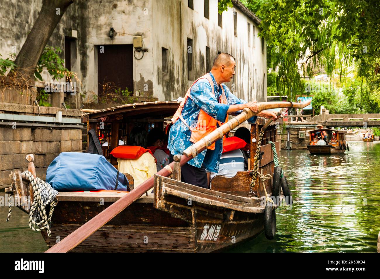 A boatman rowing a tourist boat on Pingjiang River alongside Pingjiang ...