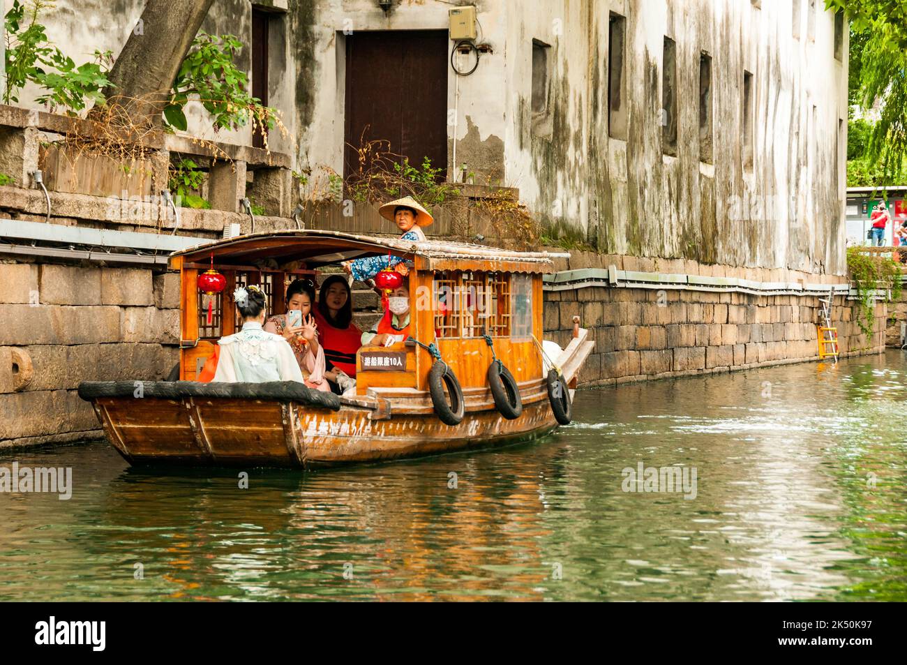 Women dressed in traditional clothes taking pictures with mobile phones on a tourist boat on ...