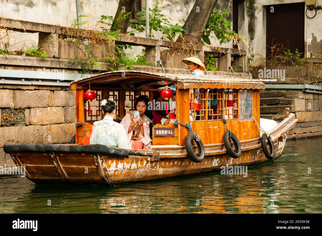Women dressed in traditional clothes taking pictures with mobile phones on a tourist boat on ...
