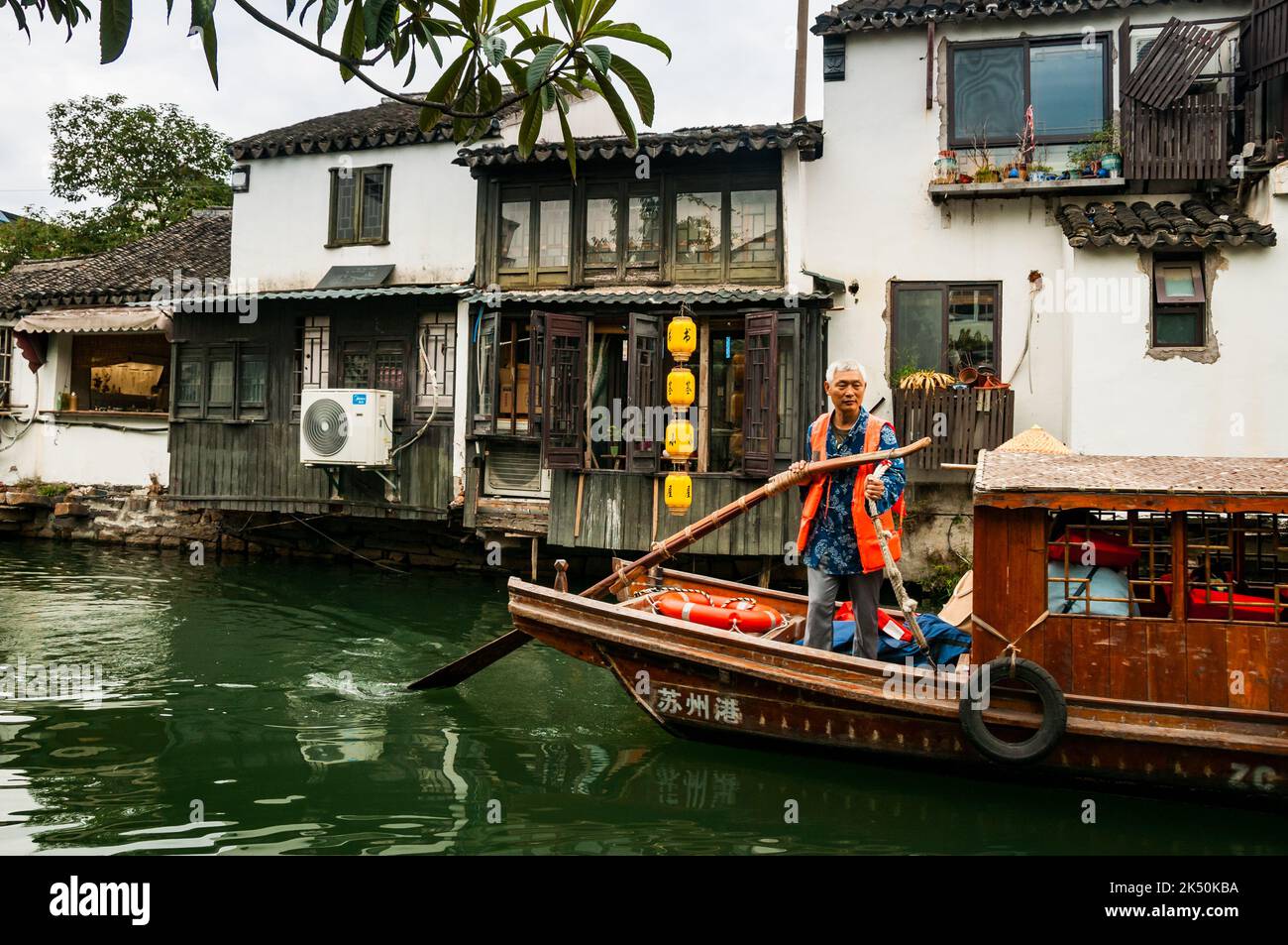A boatman rowing a tourist boat on Pingjiang River alongside Pingjiang Lu a street full of old ...