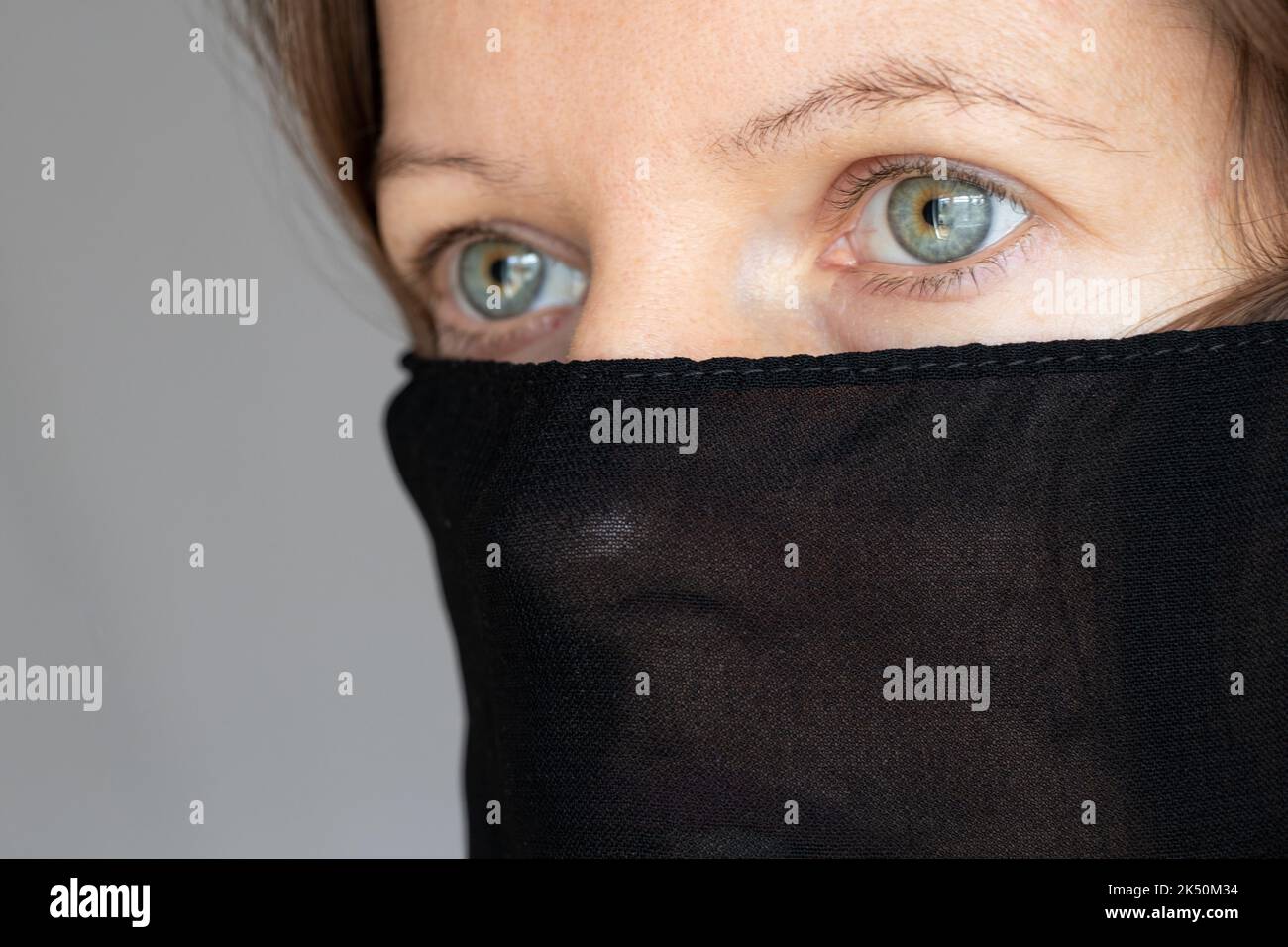 The girl covered her face and head with a black scarf on an isolated ...