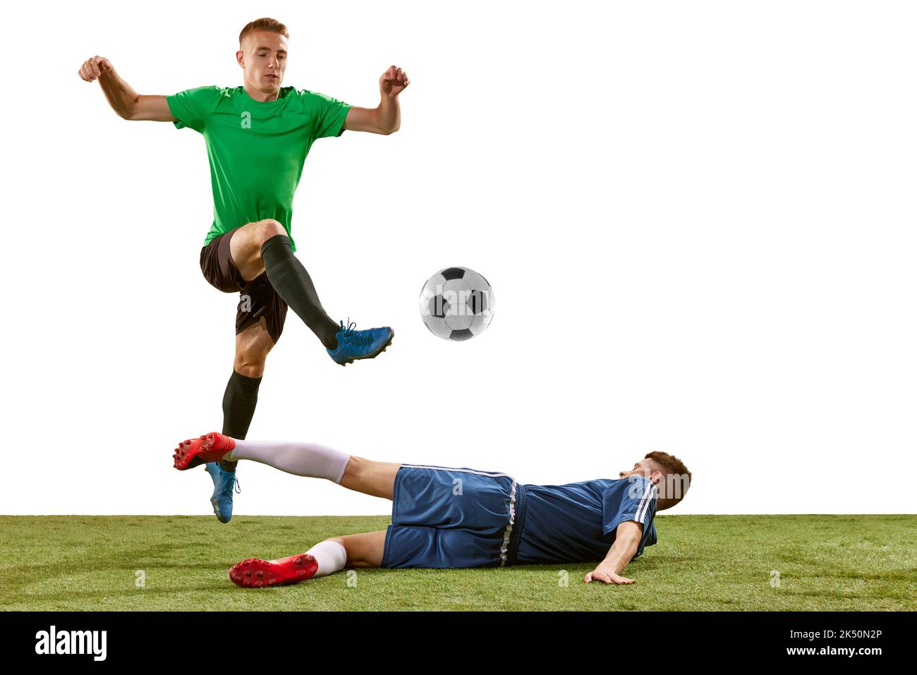 Soccer football players tackling for the ball on grass flooring over ...