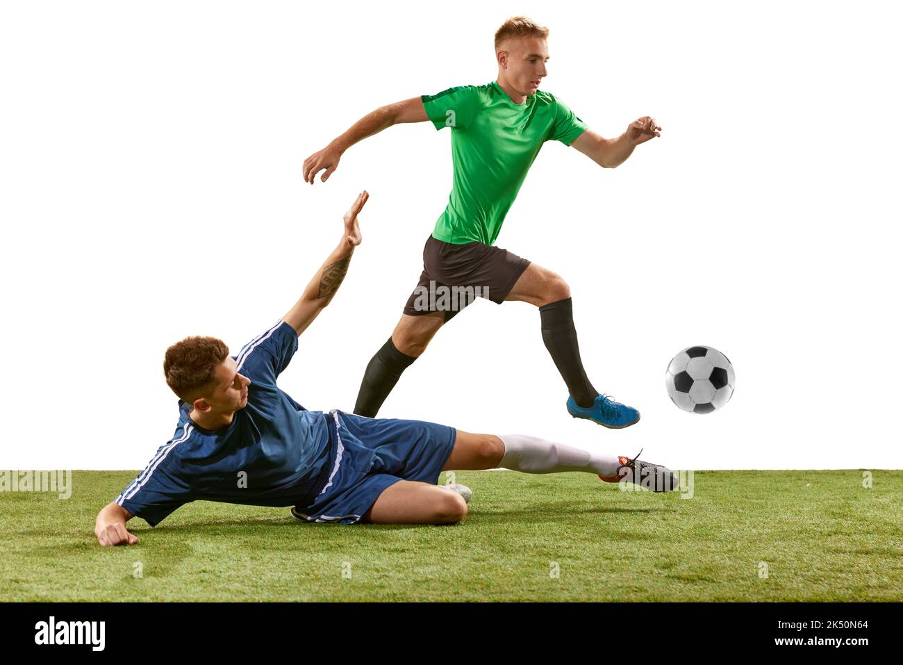 Soccer football players tackling for the ball on grass flooring over ...