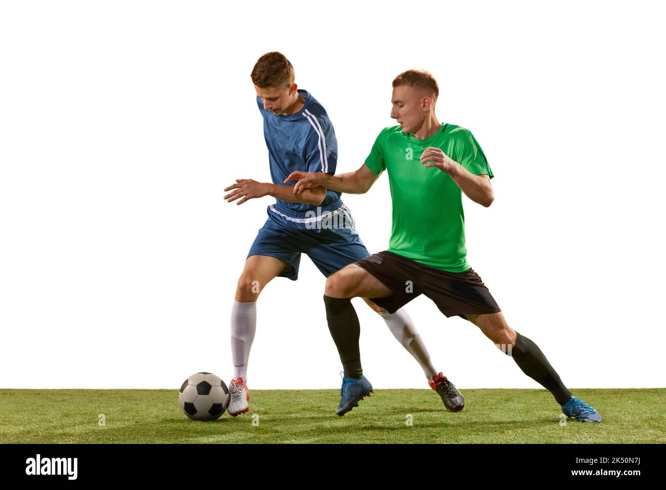 Soccer football players tackling for the ball on grass flooring over ...