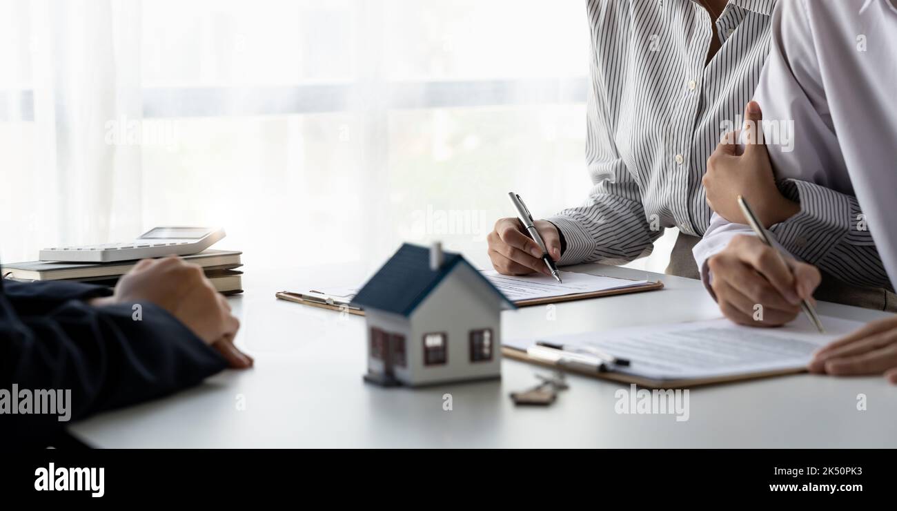 Real estate agent with couple closing a deal and signing a contract ...