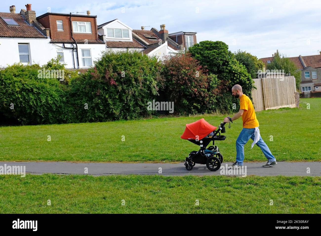 A young parent, father pushing a buggy, pram in a park Stock Photo - Alamy