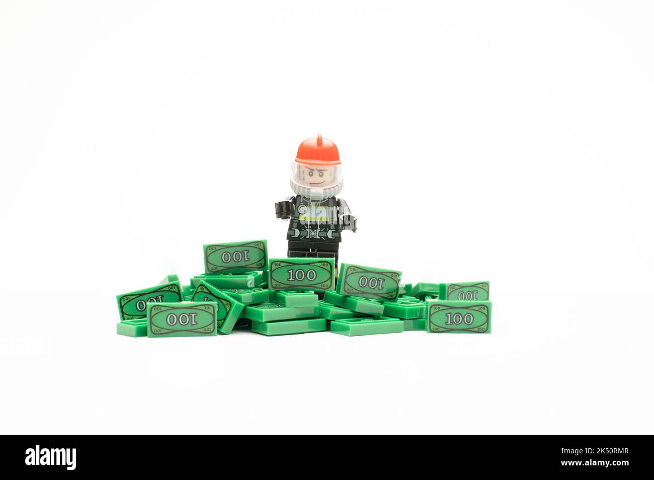 A Lego firefighter standing on a pile of money isolated on white background Stock Photo - Alamy