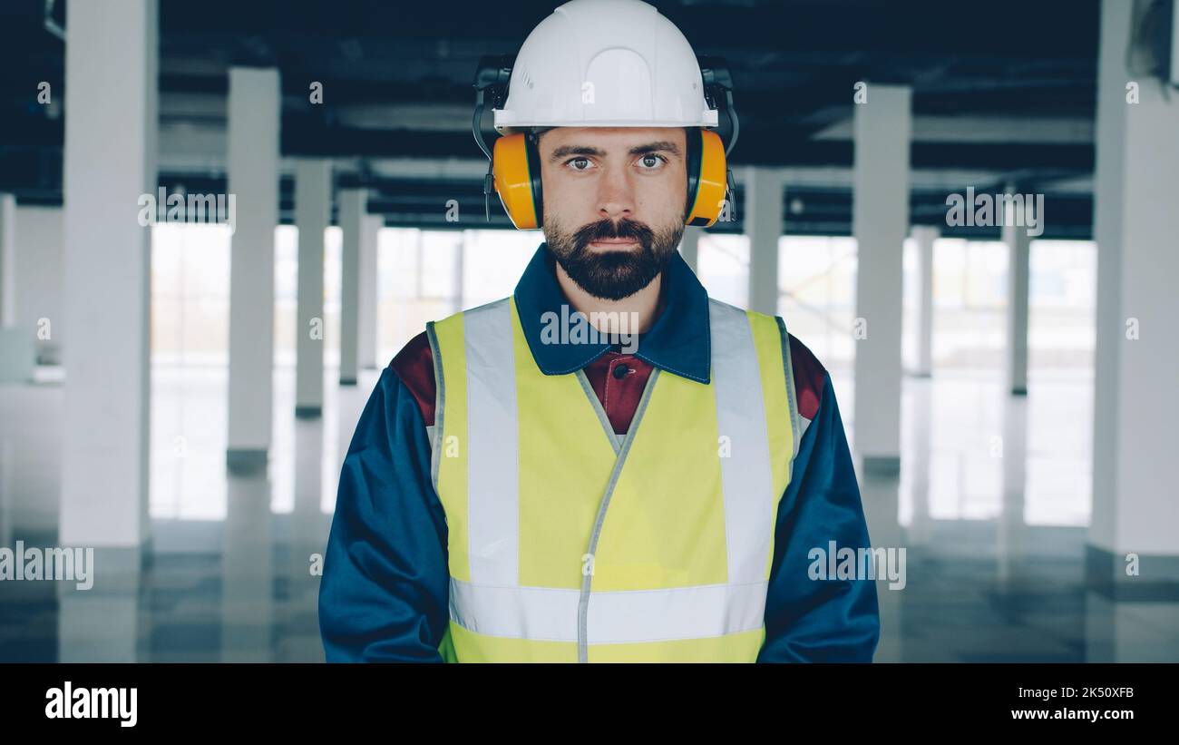 portrait of construction worker wearing safety helmet and headphones ...