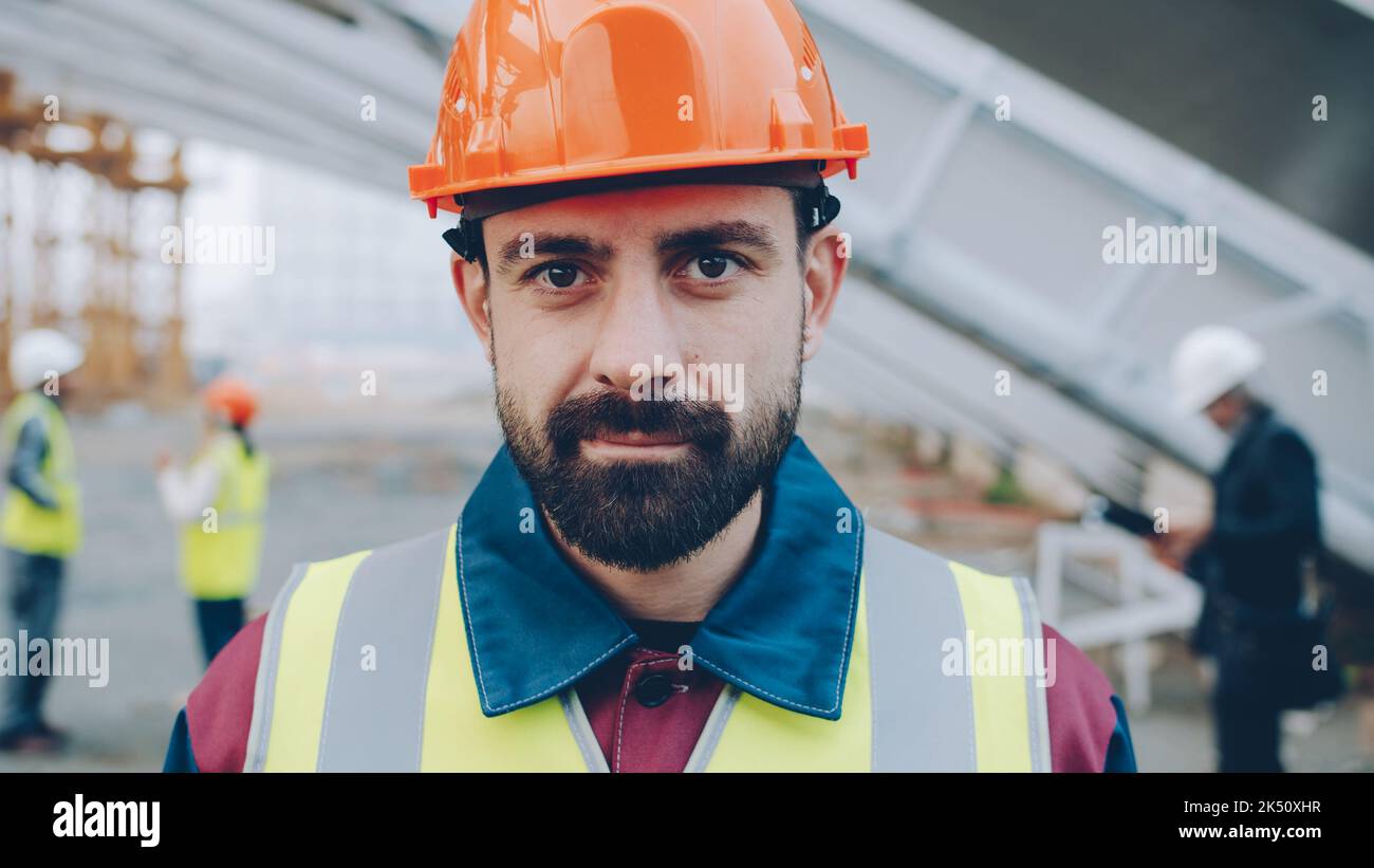 Portrait of young man engineer standing outdoors in workplace smiling ...