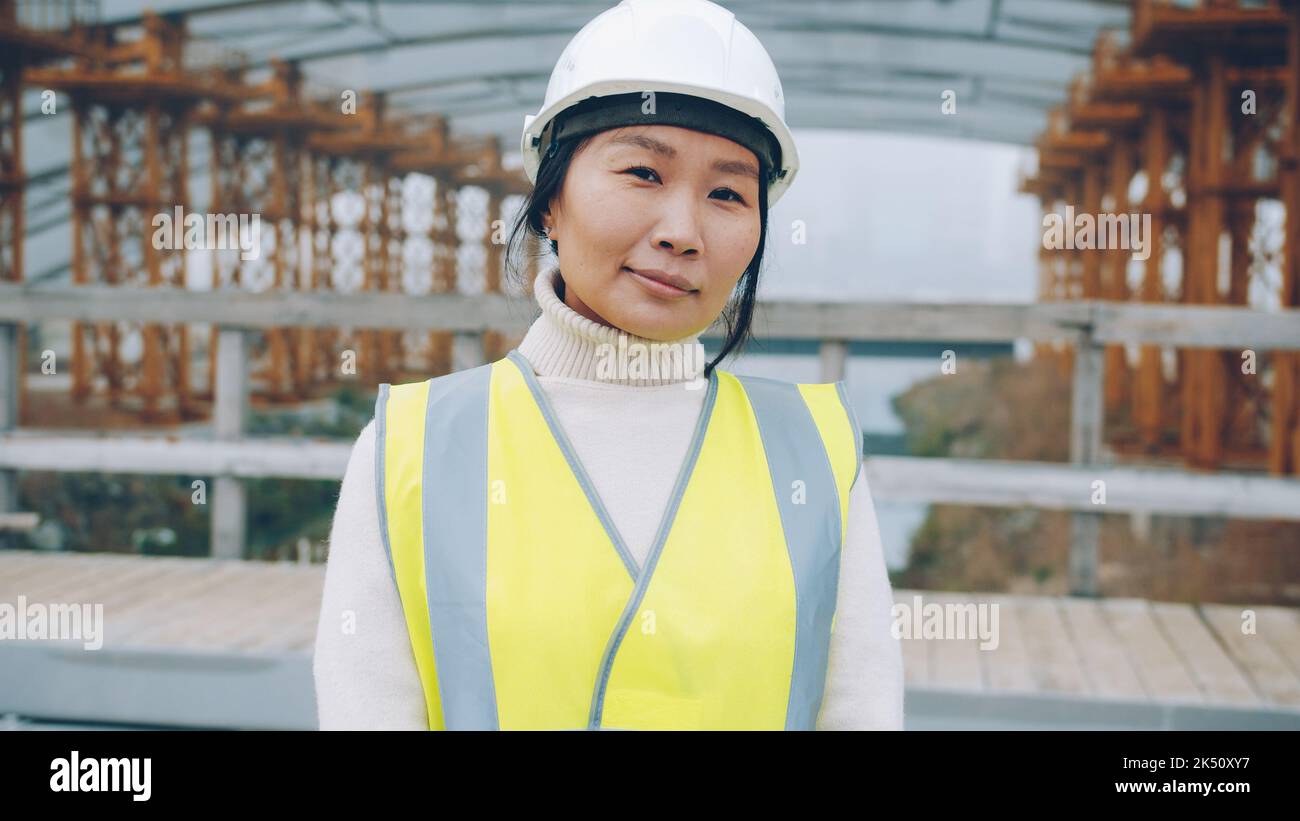 portrait of female builder standing outside construction area wearing ...