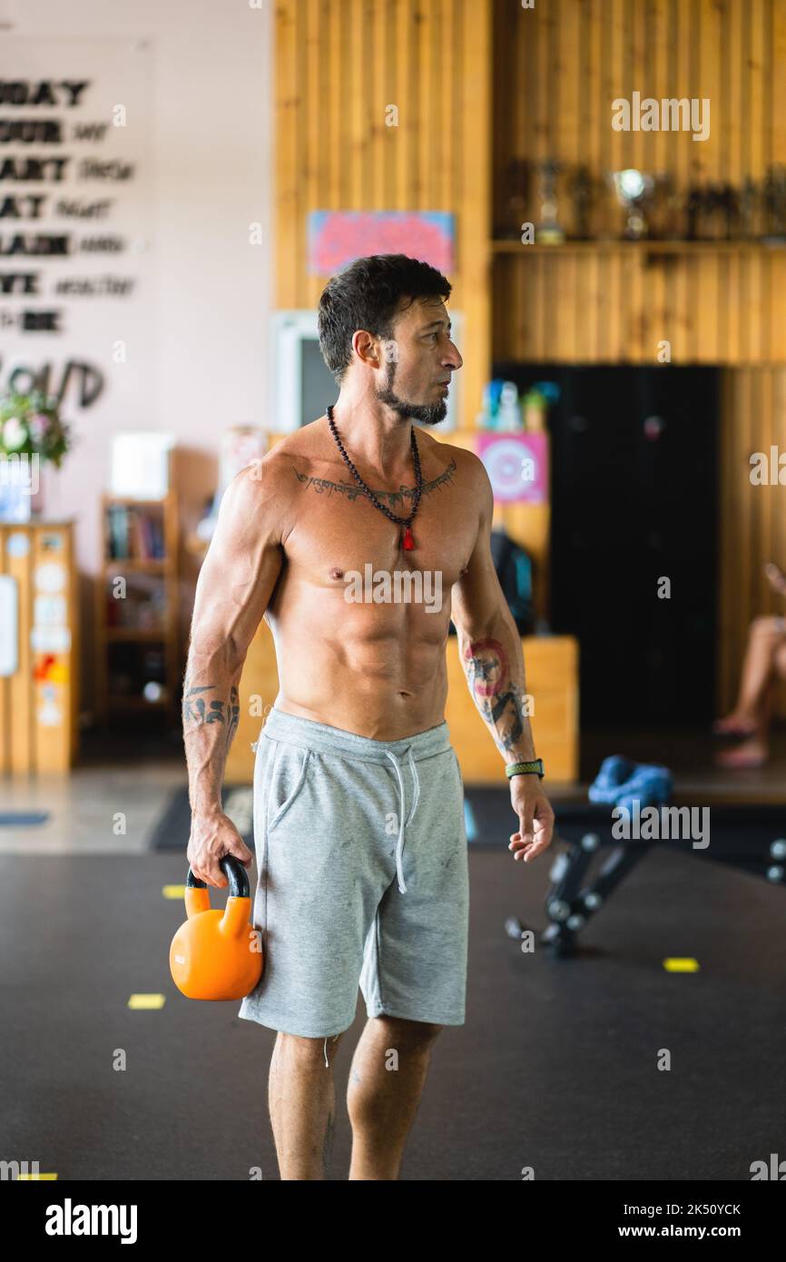Vertical photo of a man standing with a kettlebell in a gym Stock Photo ...