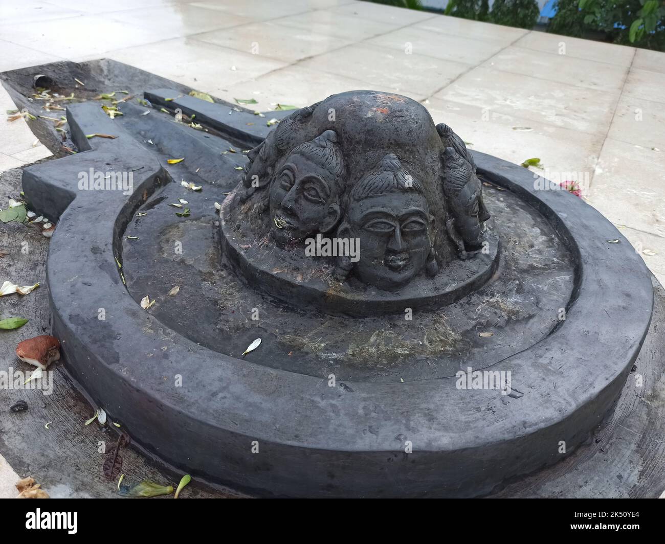 A Shiva linga made with a black stone on plane surface with surrounding ...