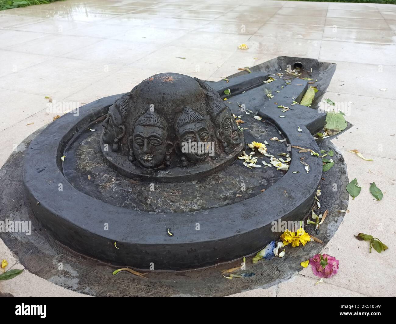 A Shiva linga made with a black stone on plane surface with surrounding ...