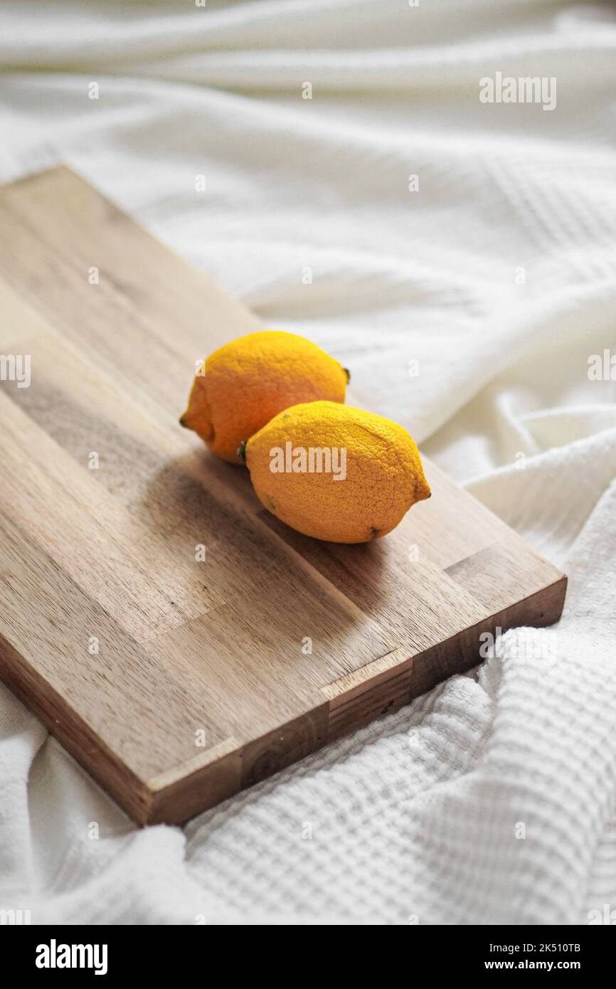 A vertical shot of two lemons on a wooden cutting board Stock Photo - Alamy