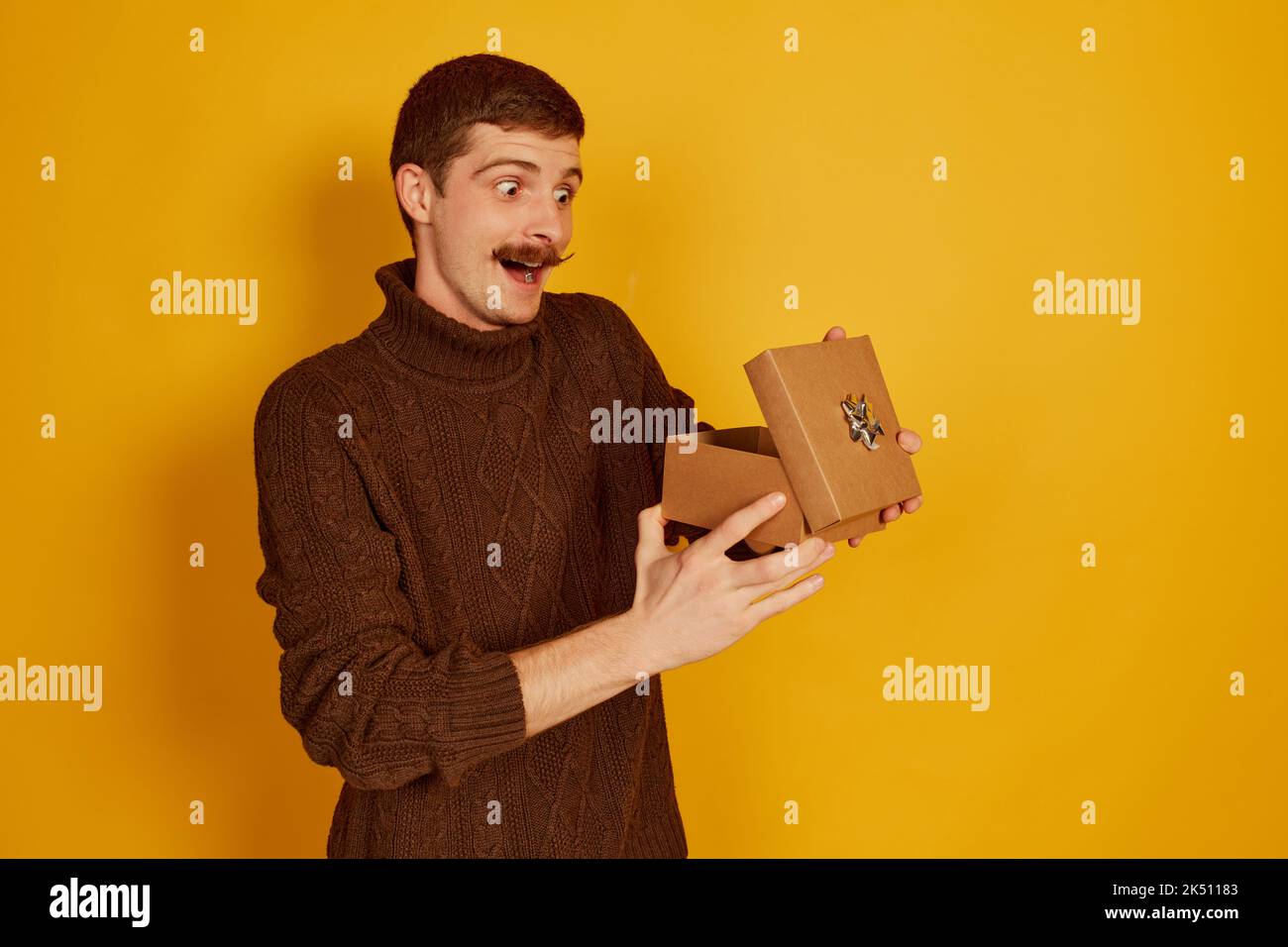 Portrait of young emotive man opening present box with surprise ...