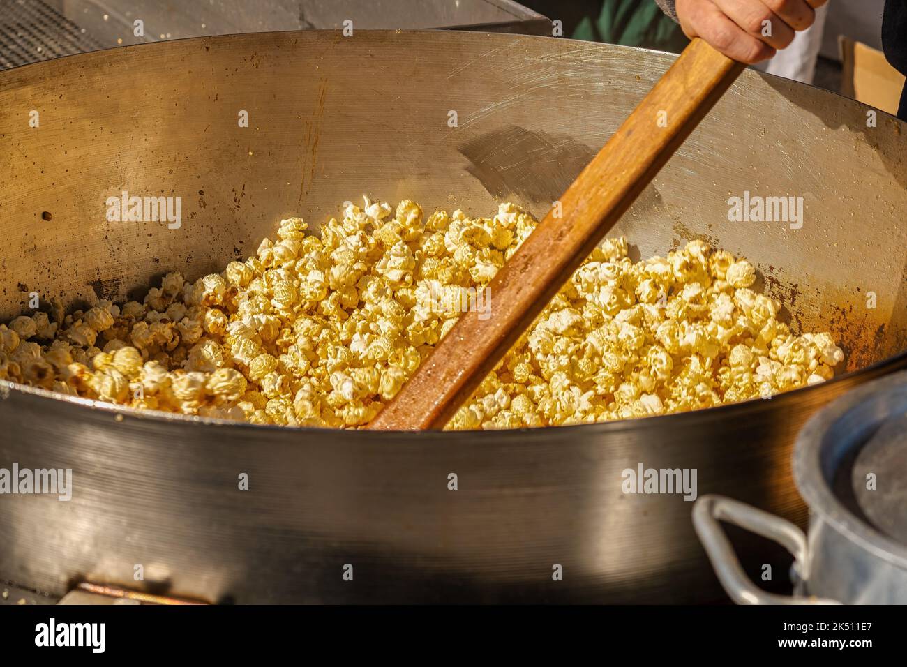 Large pot of fresh kettle corn, popcorn being stirred with a wooden ...