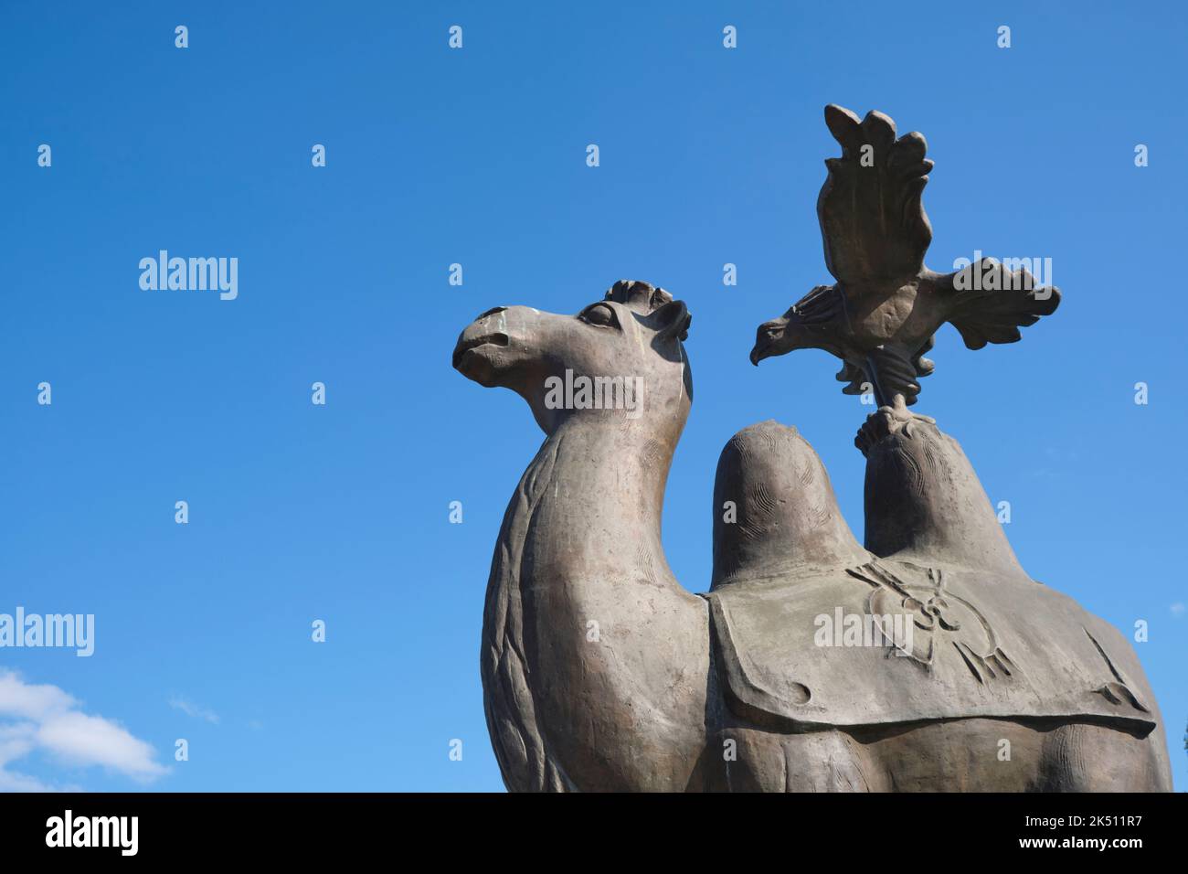A bronze sculpture of a double hump camel with a bird, falcon on its ...