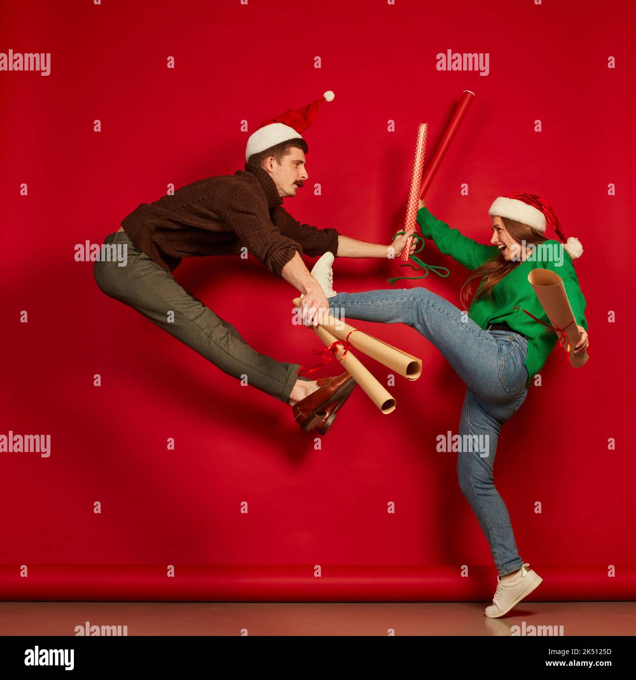 Portrait of cheerful young people, man and woman jumping with wrapping ...