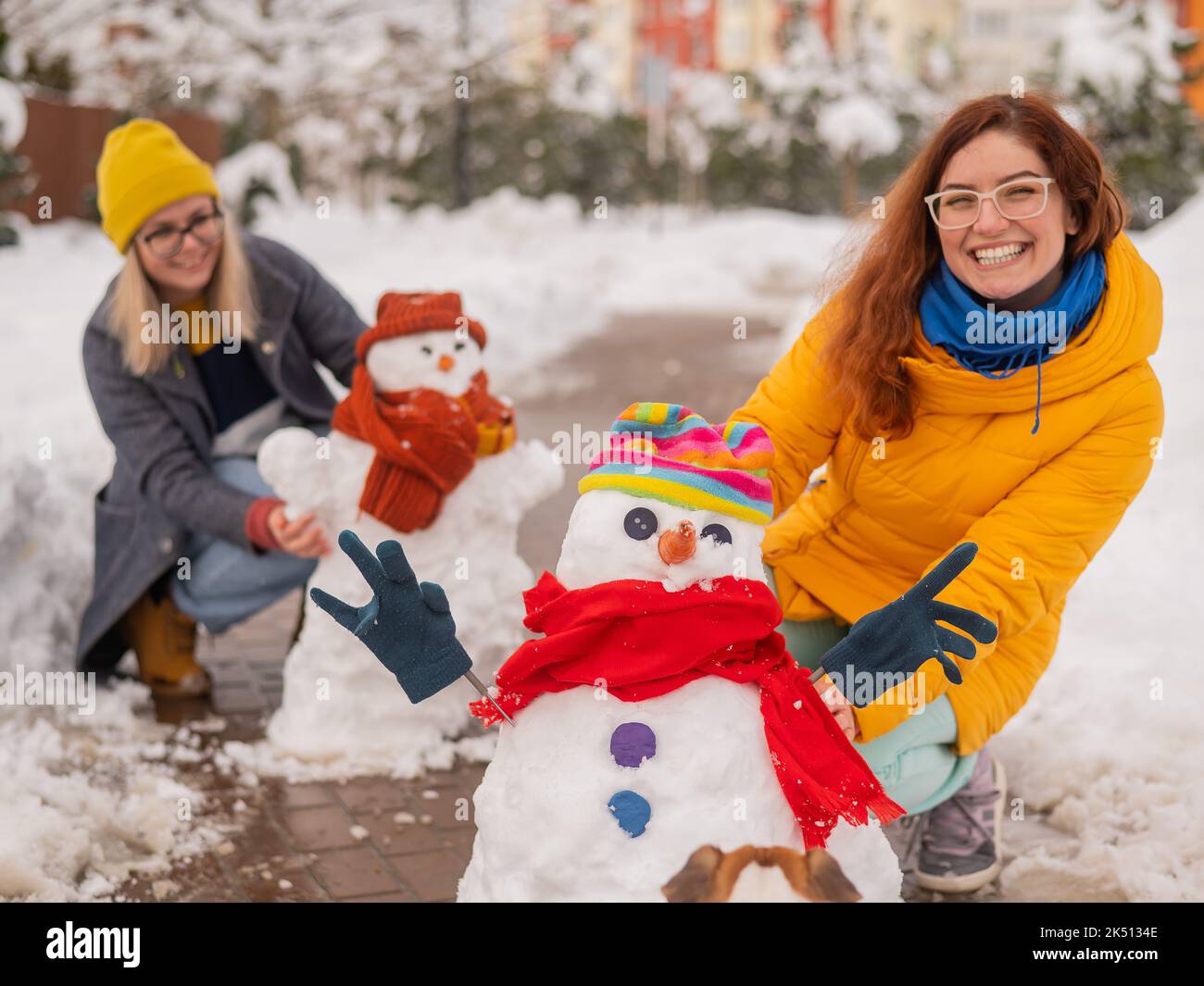 Two Caucasian women are making a snowman. Winter fun Stock Photo - Alamy