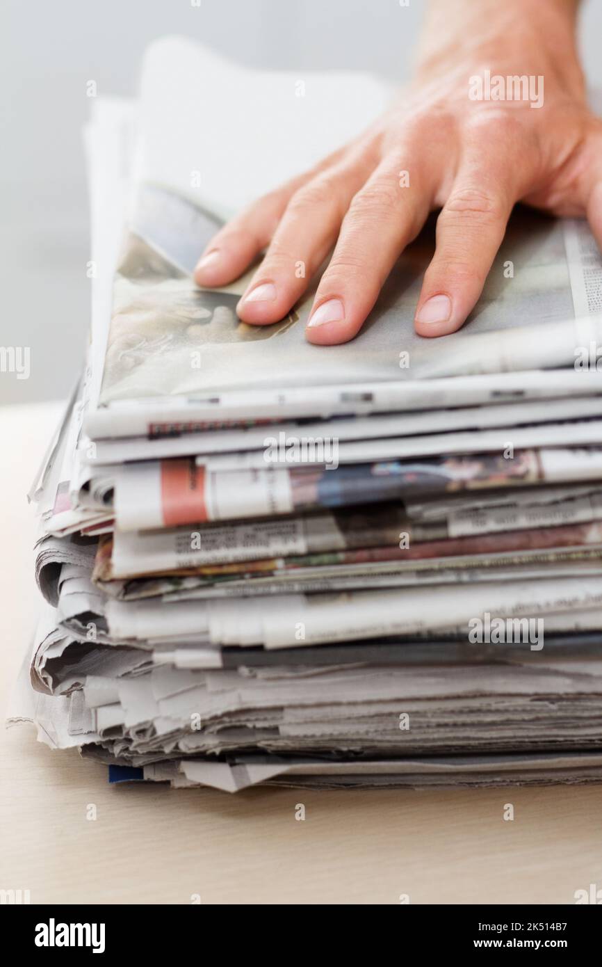 Reduce, reuse, recycle. a hand on top of a stack of newspapers Stock ...