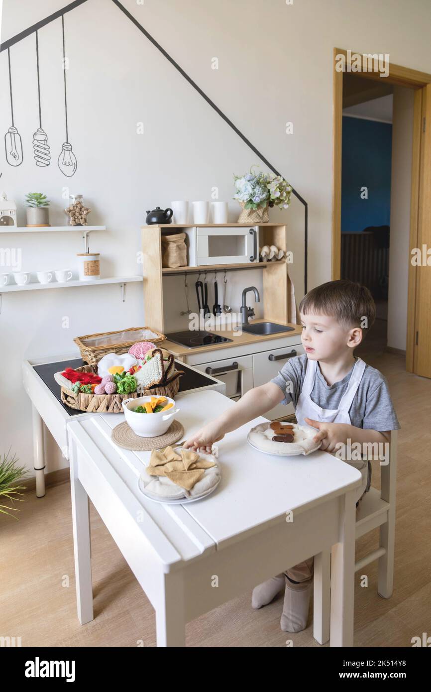 Cute little baby boy in chef hat and apron playing at childish kitchen ...