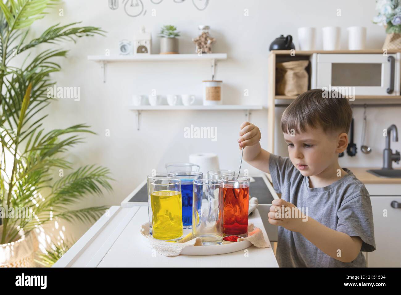 Cute baby boy learning mixing different colors with water and paint in ...