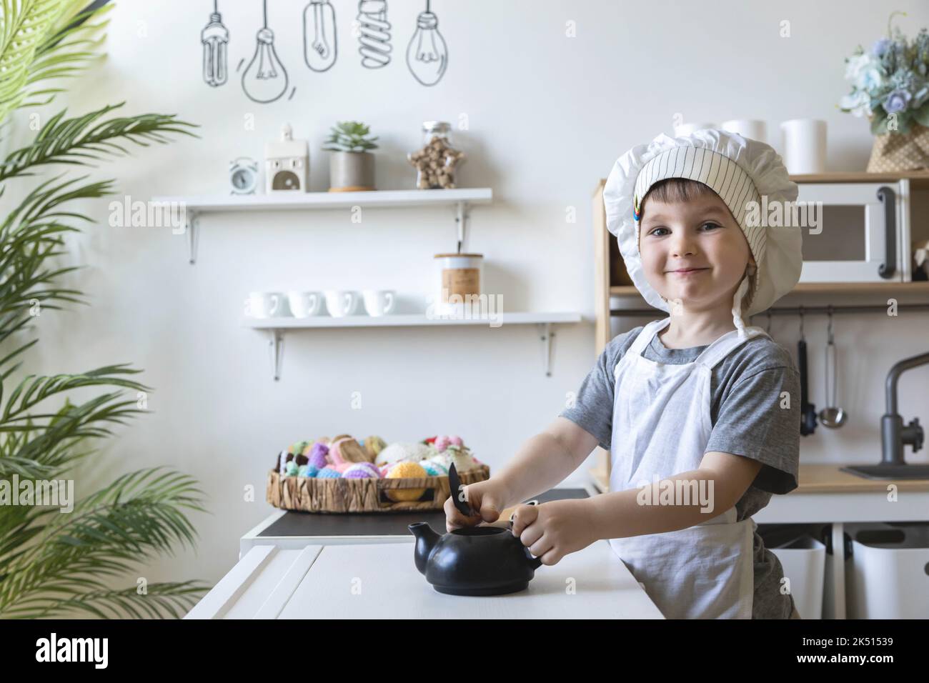 Cute little baby boy in chef hat and apron playing at childish kitchen ...