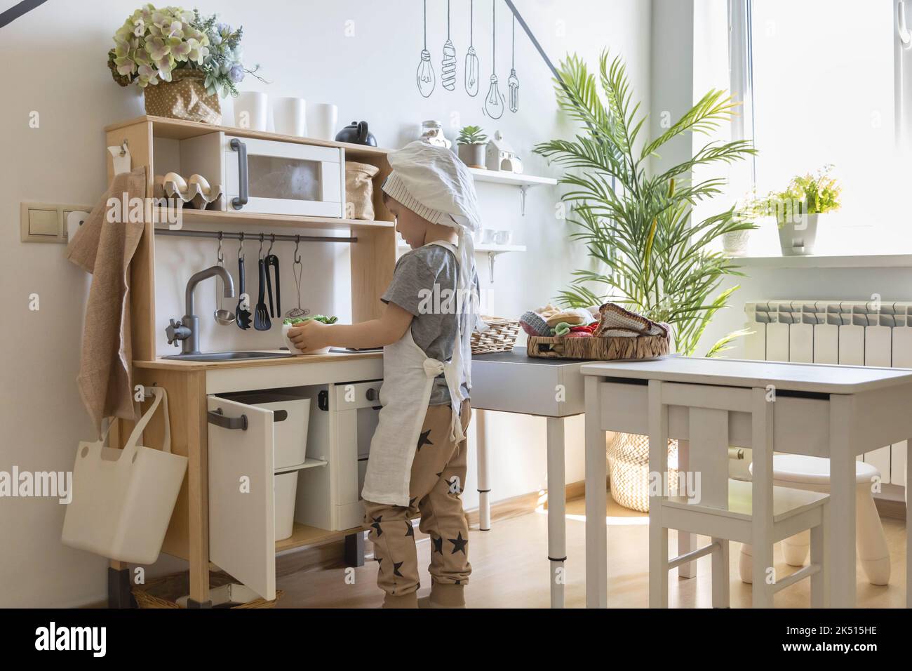 Cute little baby boy in chef hat and apron playing at childish kitchen ...