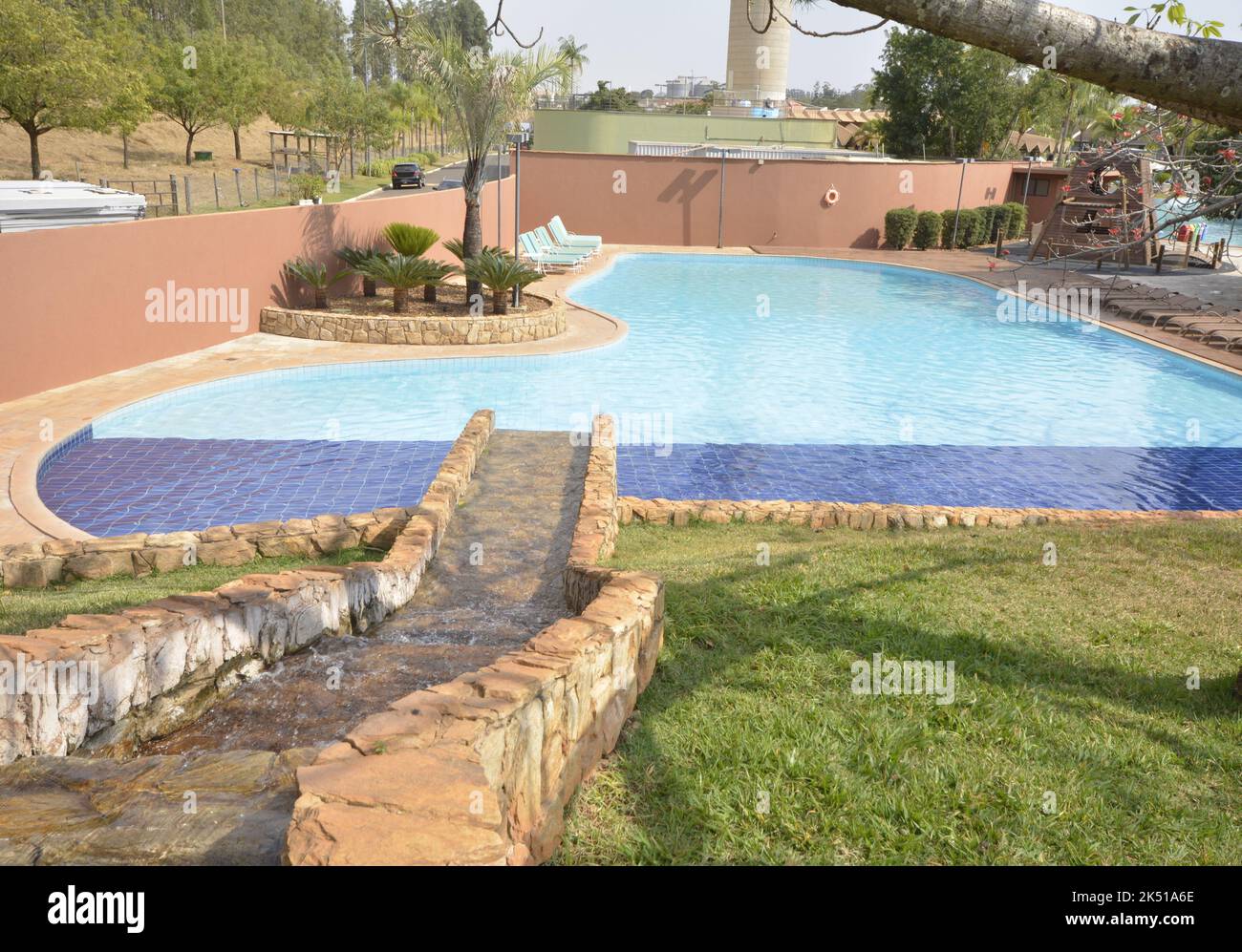 Resort. Luxury resort pool with waterfall and sun loungers on a clear ...