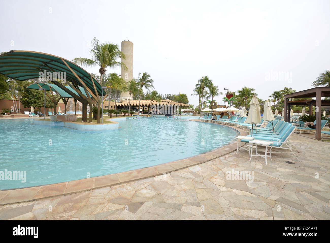 Tourists at a luxury resort pool with waterfall and sun loungers in the ...