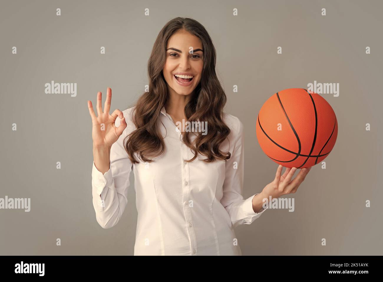 Happy woman with ok sign hold basketball ball, isolated on gray ...