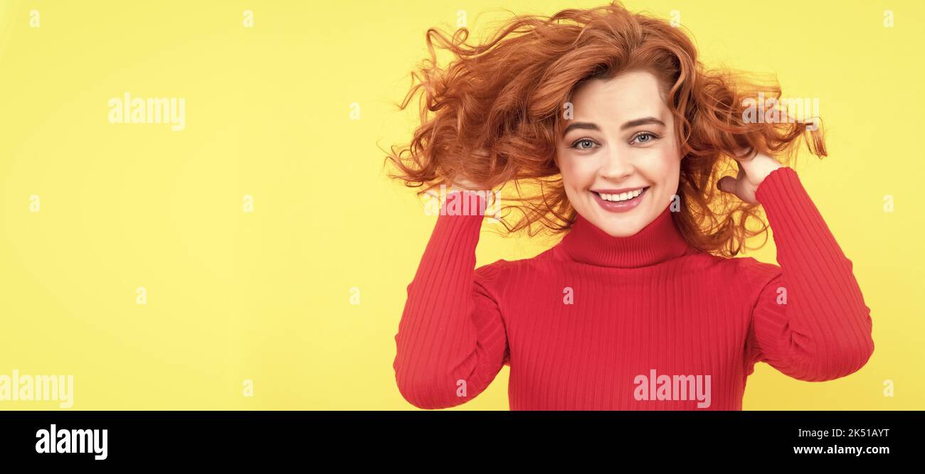 happy redhead woman with windy curly hair on yellow background ...